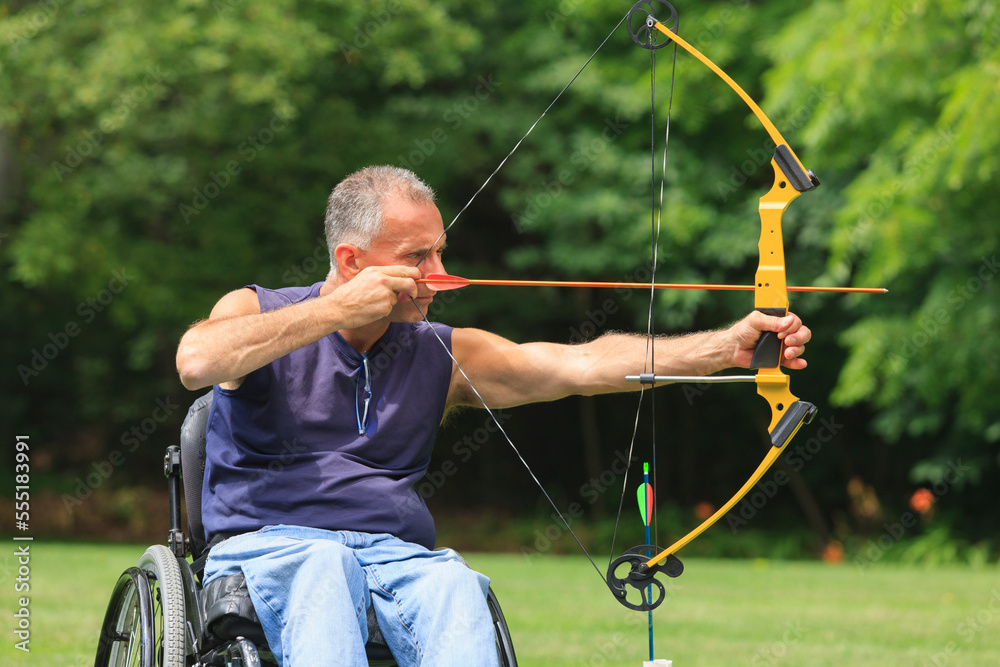 Man with spinal cord injury in wheelchair aiming his bow and arrow for ...