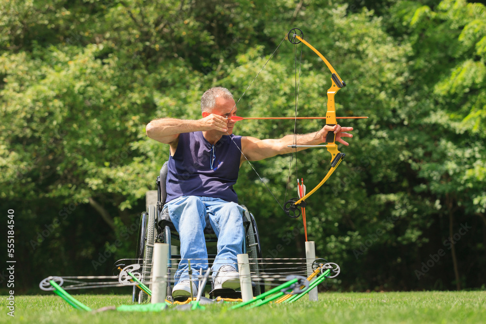 Man with spinal cord injury in wheelchair aiming his bow and arrow for ...