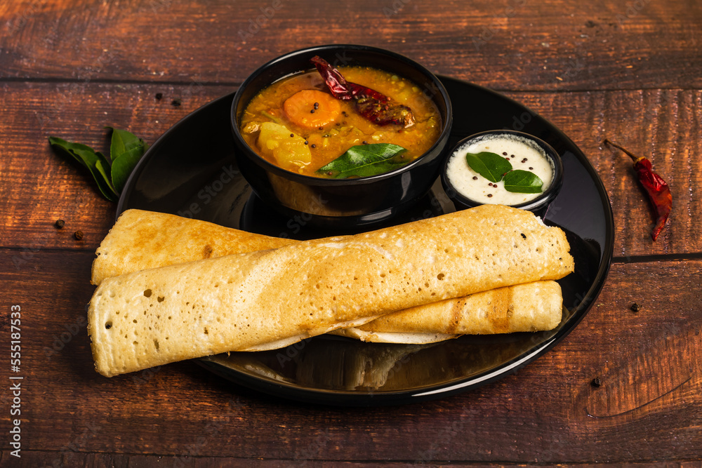 Crispy Dosa or Little Millet Dosa on a black plate. Served with sambar ...