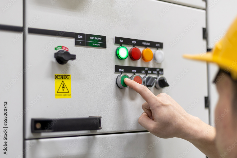 Engineer's finger is pressing a button to test a system in front of a ...