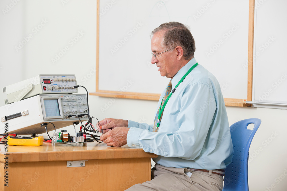 Professor wiring oscilloscope connections in electronics classroom ...