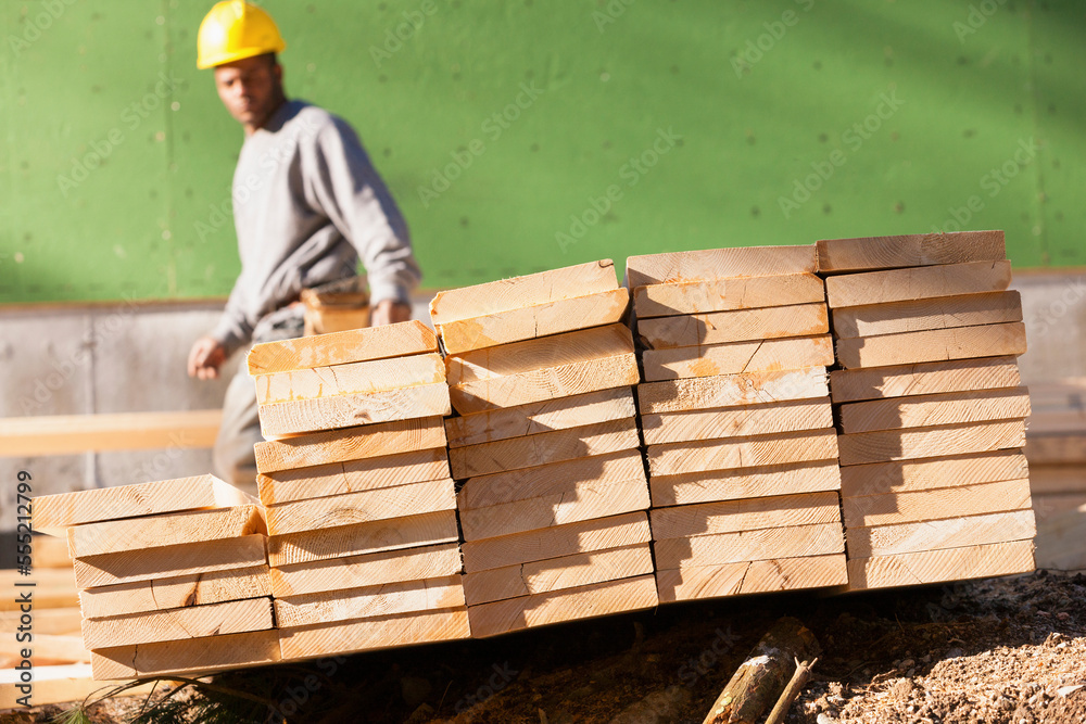 Stack of rafters with a carpenter in the background Stock Photo | Adobe ...