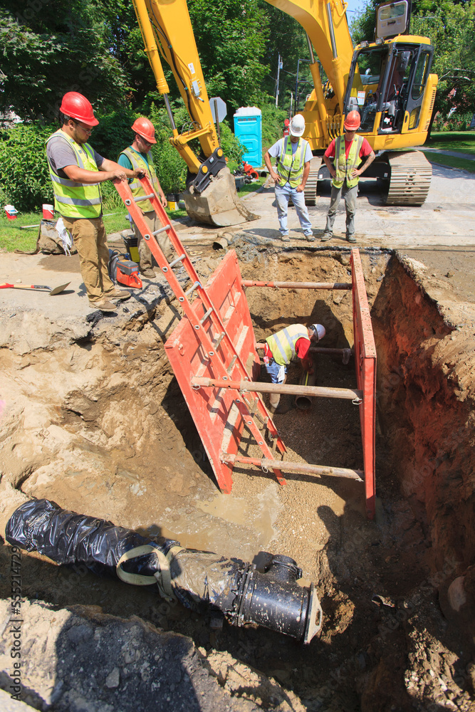 Construction workers measuring length of pipe while protected by ...