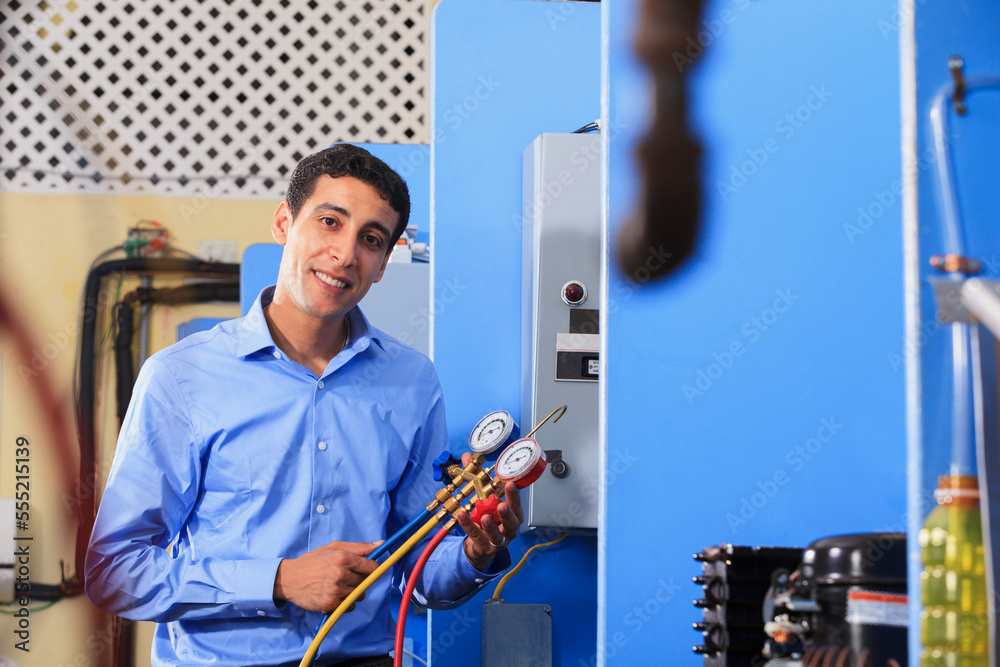 Student demonstrating air conditioner recharging manifold with gauges ...