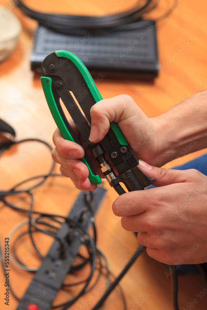 Cable installer using a crimping tool to add a new cable connector to a ...