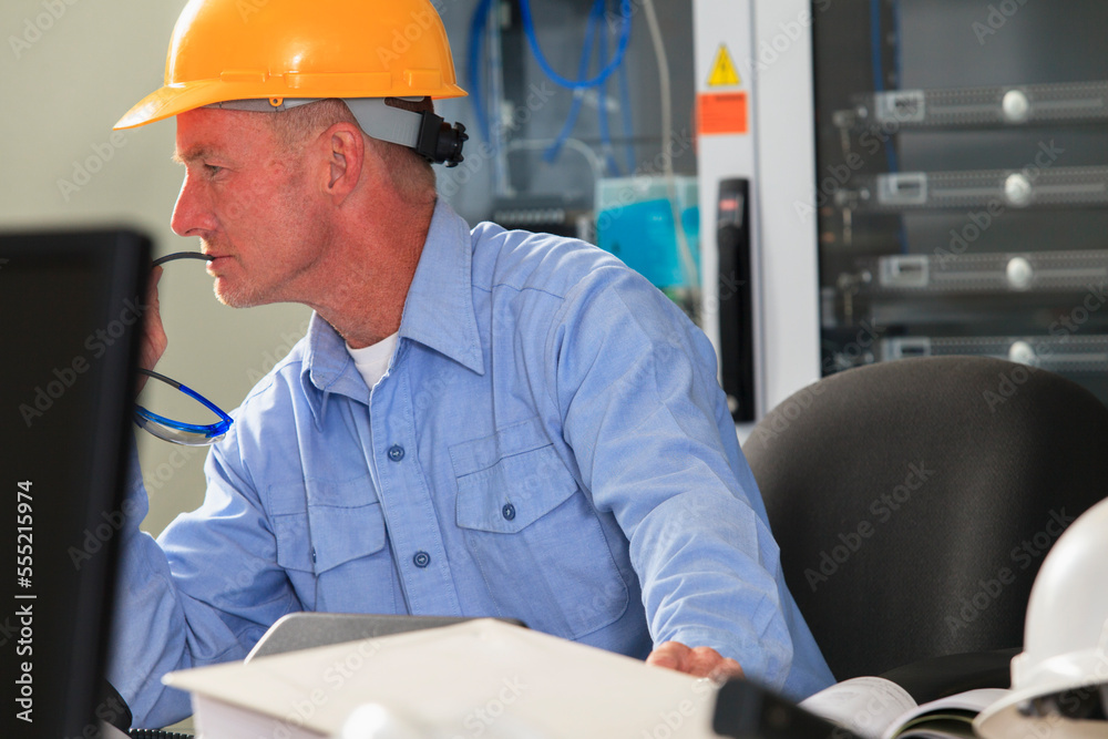Electrical engineer studying monitor for performance in operations room ...