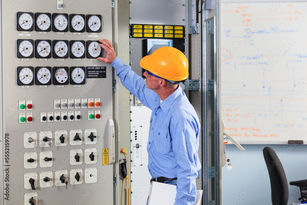 Electrical engineer inspecting power plant controls in central ...