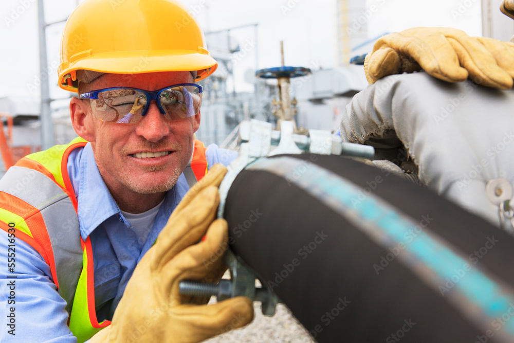 Engineer at electric power plant examining hose for water supply to the ...