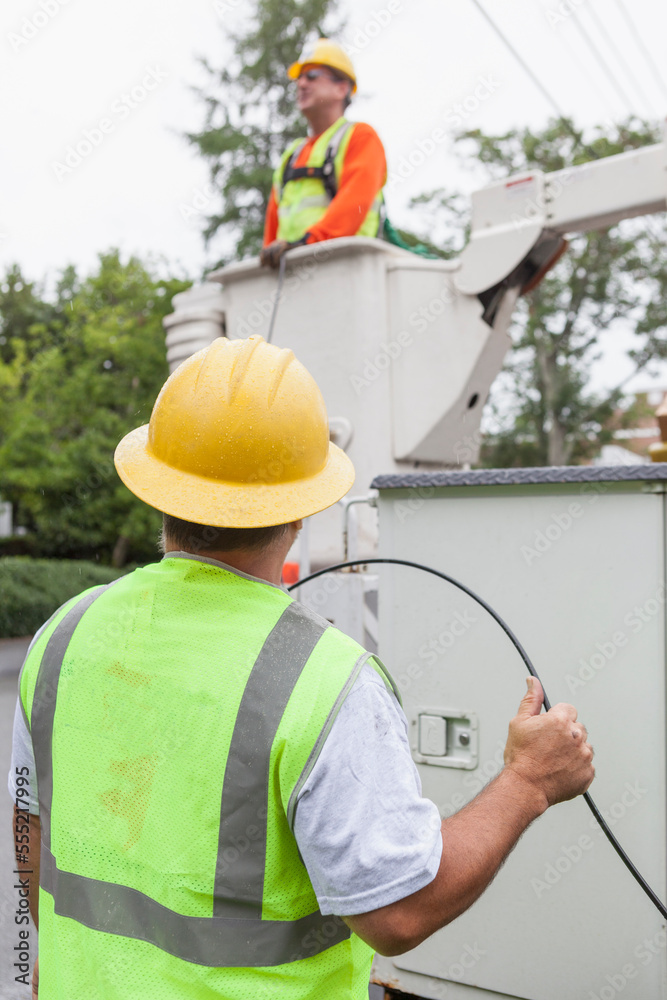 Utility workers preparing to work on power lines in a bucket truck ...
