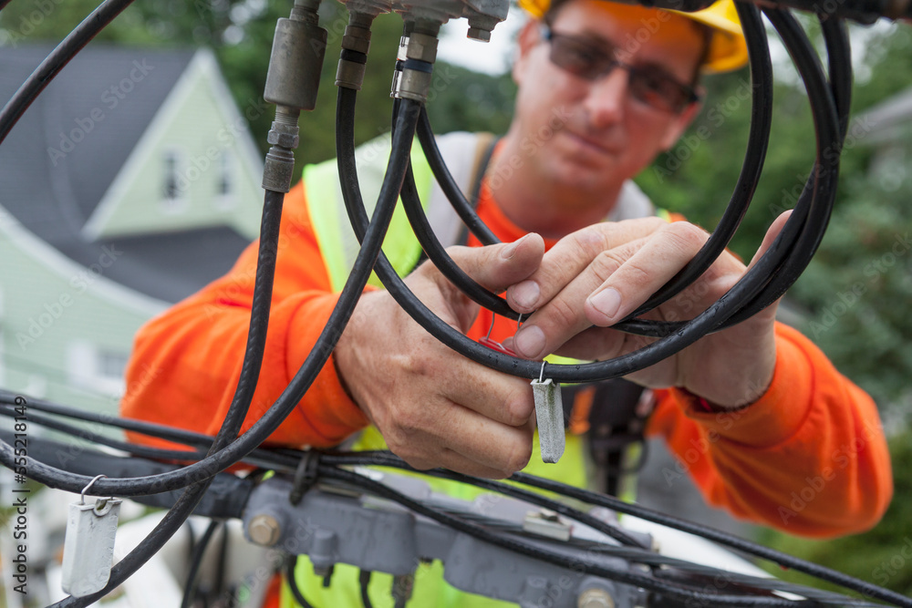 Cable lineman attaching identification tag to cable from bucket lift ...