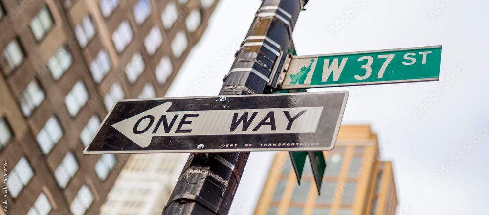 Street signs on a post, a directional one way and West 37th Street ...