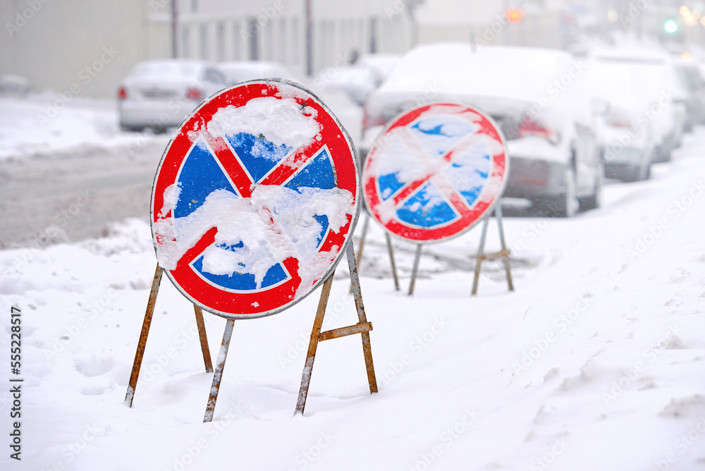 No parking road sign covered with snow at roadside on snowy road. Car ...