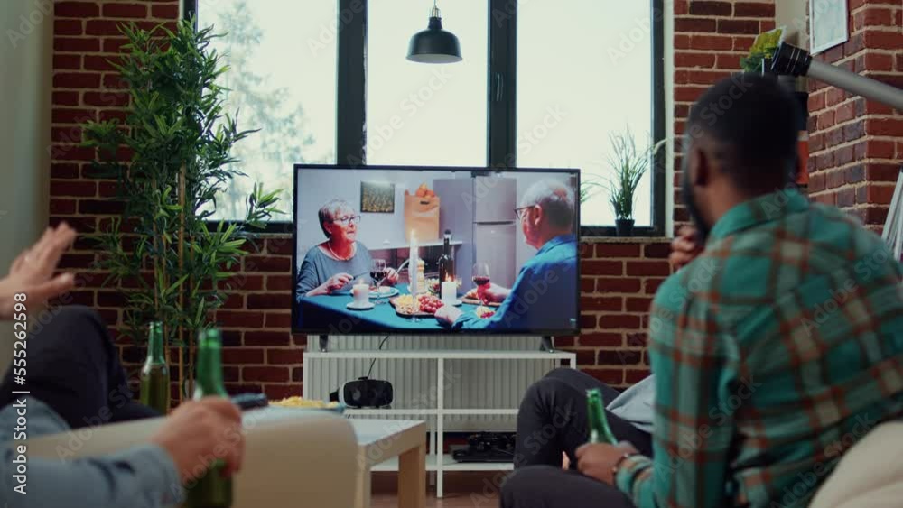 Diverse people having fun watching drama movie on television, drinking ...