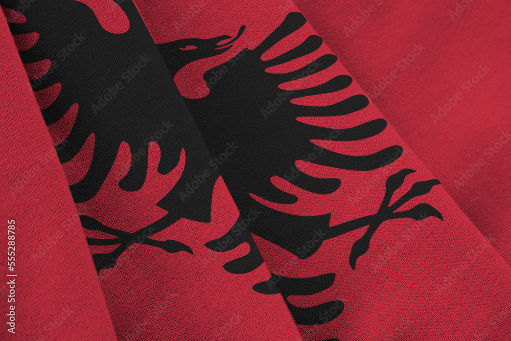 Albania flag with big folds waving close up under the studio light ...