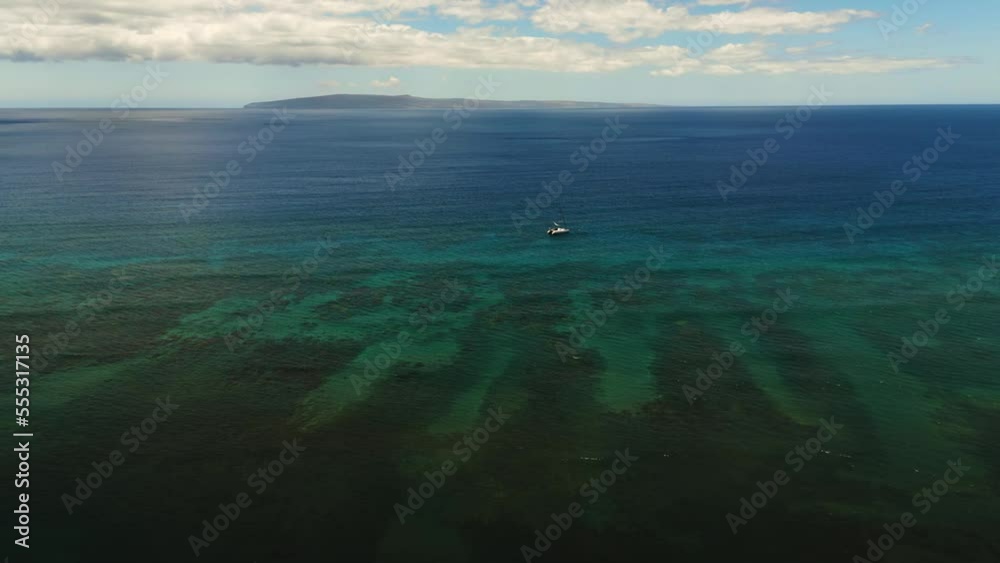 Lone sailboat floating above coral reef along coast of Maui Hawaii with ...