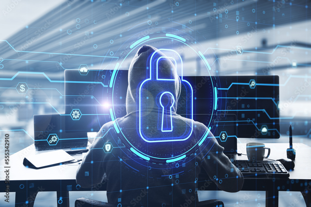 Back view of hacker using laptop computer at desktop with glowing ...