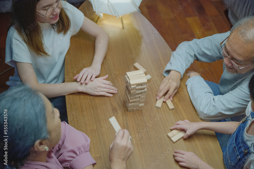 Happy grandparents Asian family enjoy playing toy block with little daughter together in home ...