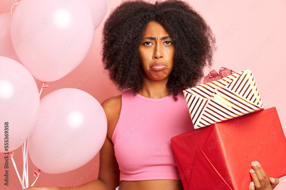 Disappointed and lonely dark skinned woman, holds presents with sad ...