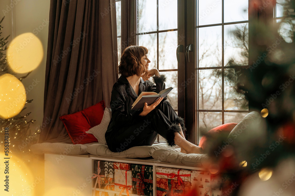 Stockfoto Woman christmas window. A beautiful brunette woman in black ...