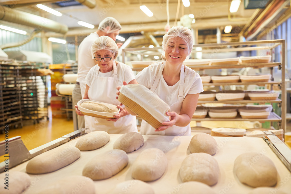 Baker as an apprentice and older colleague baking bread Stock Photo ...