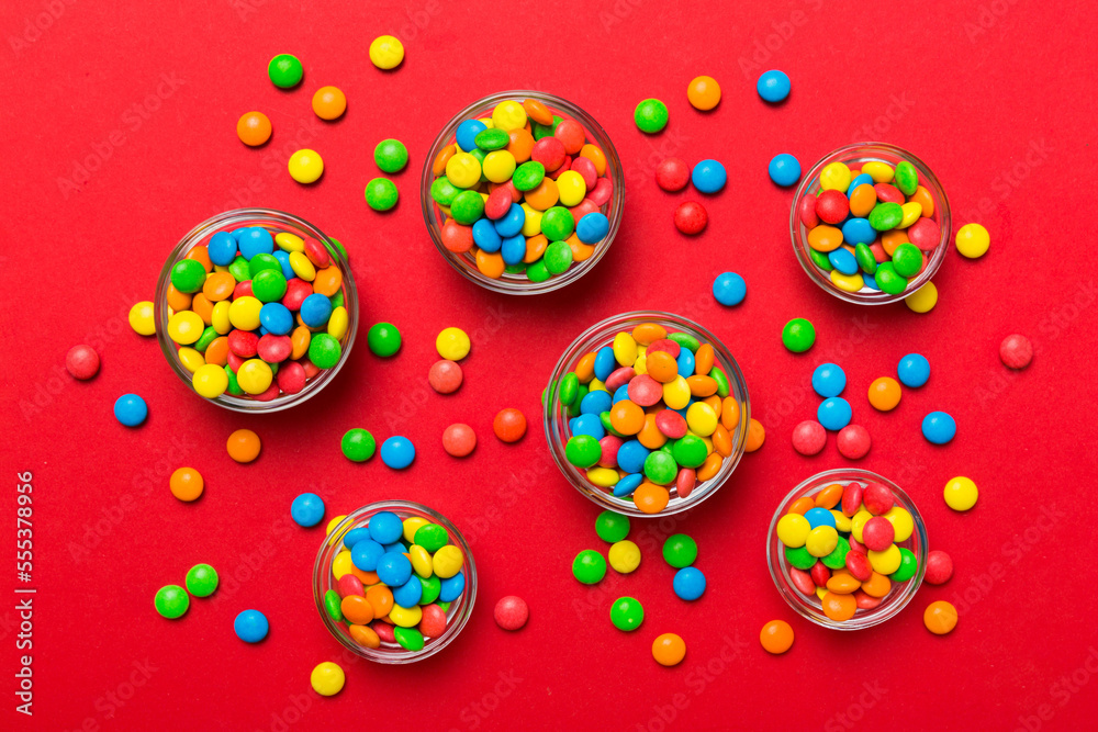 different colored round candy in bowl and jars. Top view of large ...
