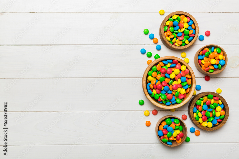 different colored round candy in bowl and jars. Top view of large ...