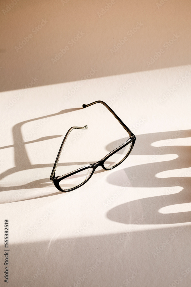Black eyeglasses on beige background with shadows top view. Optic store ...