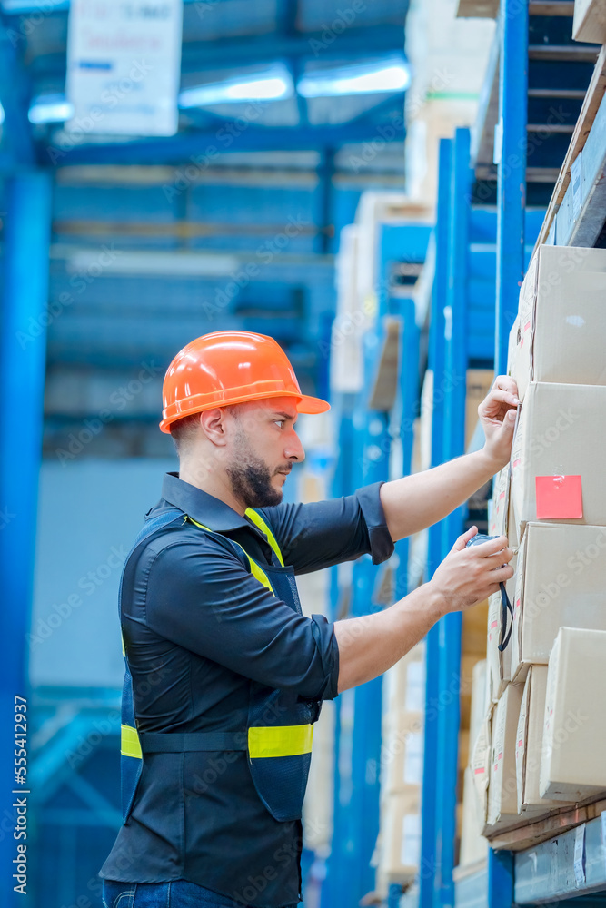 Warehouse workers in helmets checking goods and supplies on shelves ...