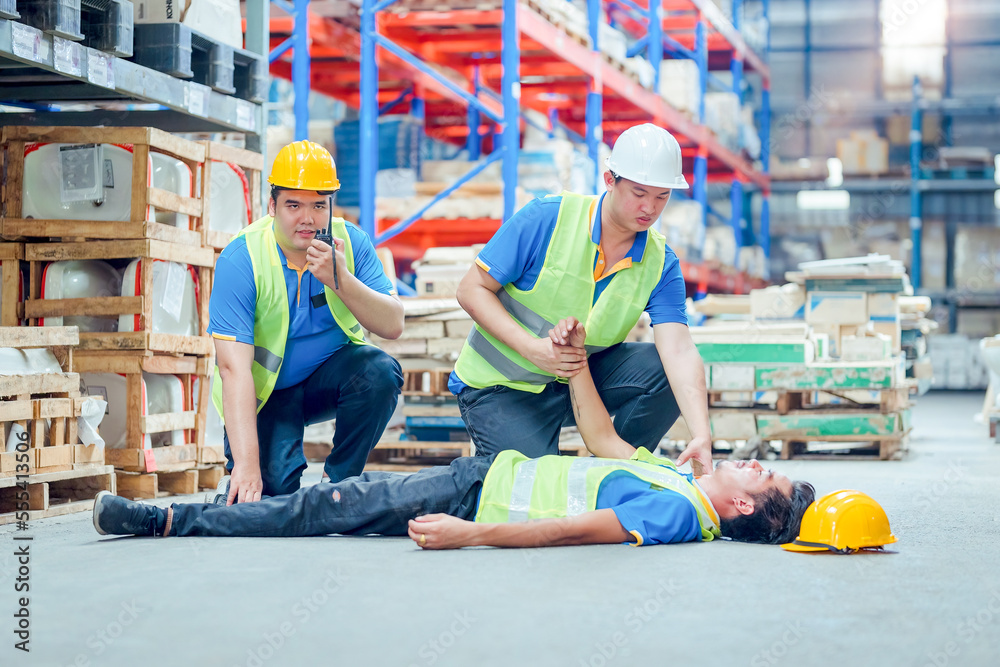 Panoramic Warehouse worker do first aid to his colleague lying down on ...