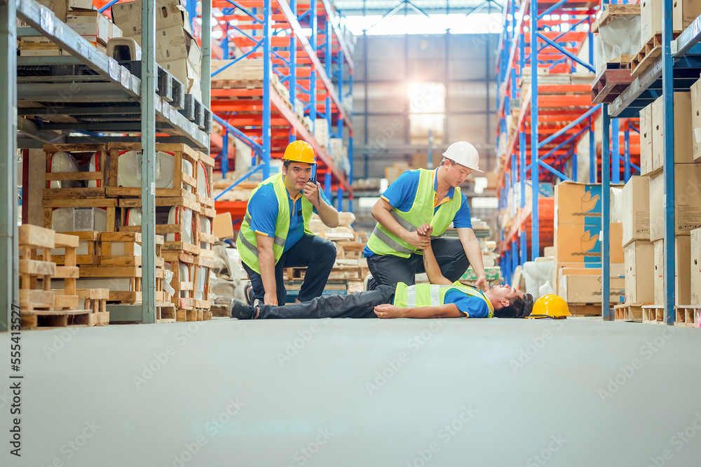 Panoramic Warehouse worker do first aid to his colleague lying down on ...