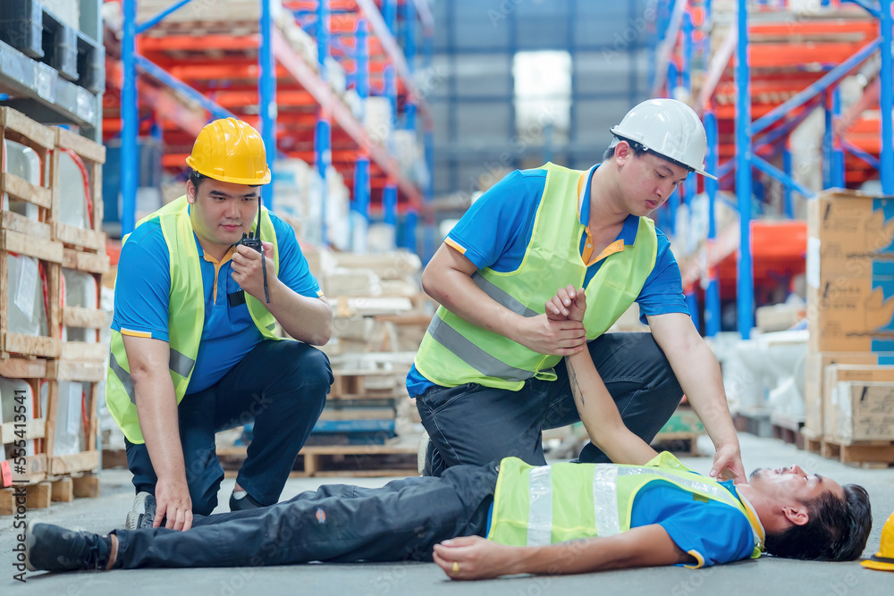 Panoramic Warehouse worker do first aid to his colleague lying down on ...
