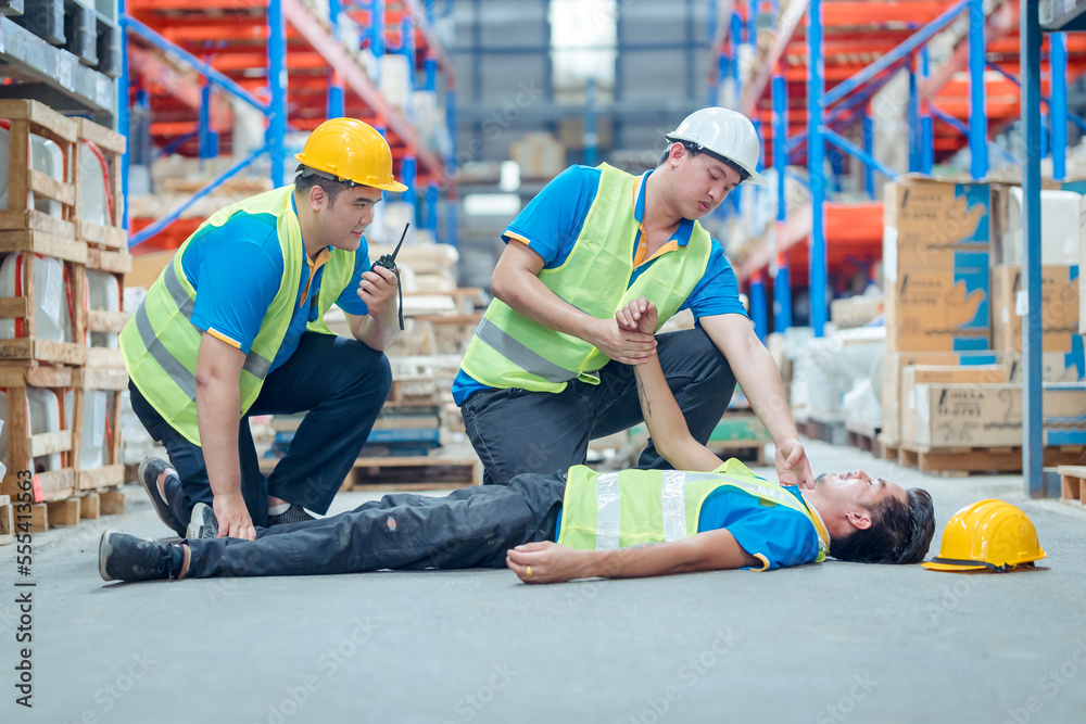Panoramic Warehouse worker do first aid to his colleague lying down on ...