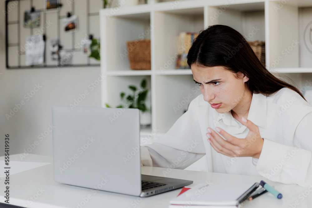 Foto de Angry young woman at home office desk work online on computer ...