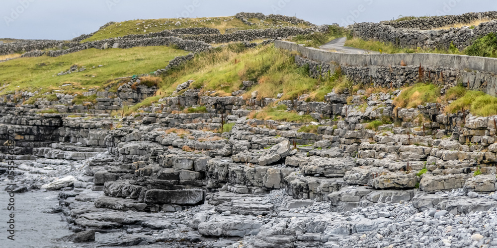 Stone walls and a road along the coast of Inishmore, the largest of the ...