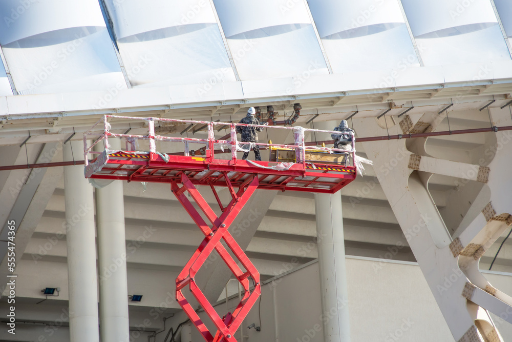 Construction workers standing in the scissors lifting crane bucket ...
