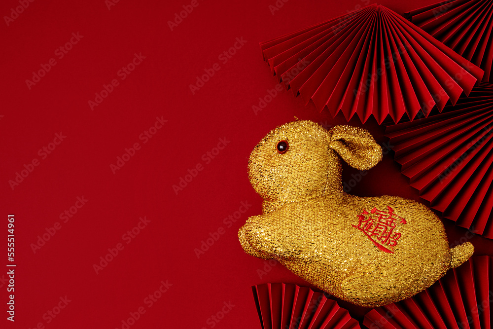 Golden rabbit over red background with paper fans. Text on hare means ...