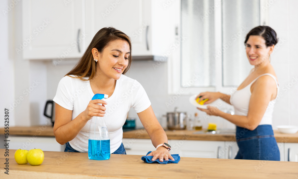 Positive interested young latin american woman with sister cleaning ...