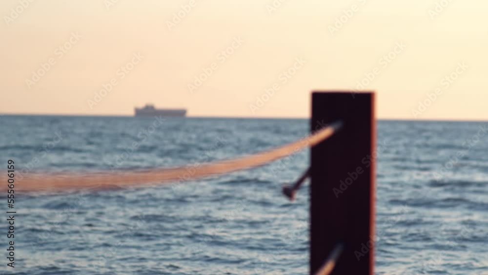 Wooden pier with posts and ropes on the sea shore with the sparkling ...