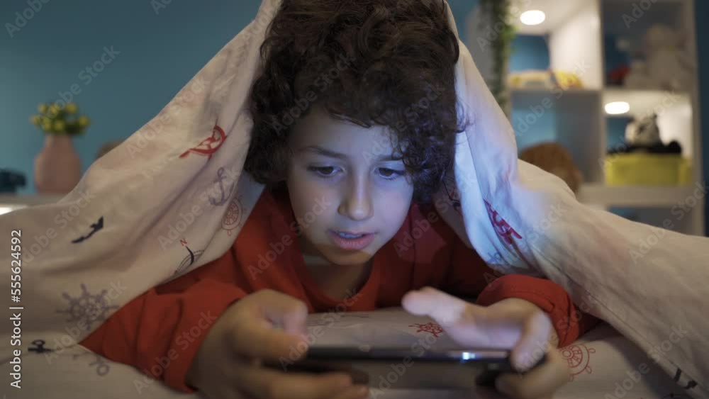 Phone addicted boy secretly plays on the phone. The boy, whose phone is ...