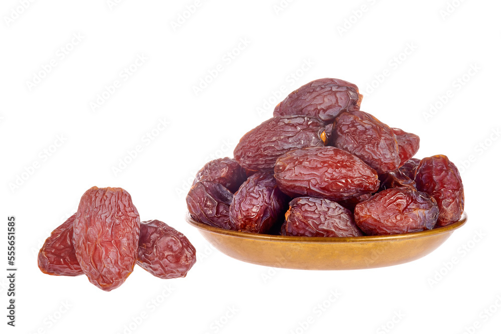 A pile of dried dates lies in a copper plate. Three dates lie side by ...