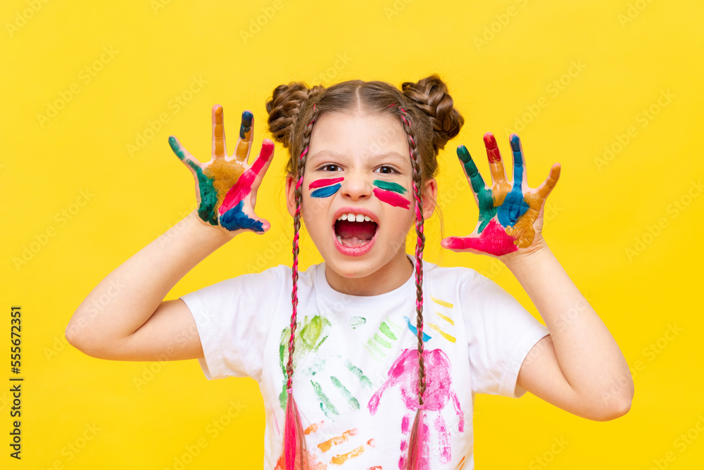 A little girl stained in multicolored paints, portrays a growling beast ...
