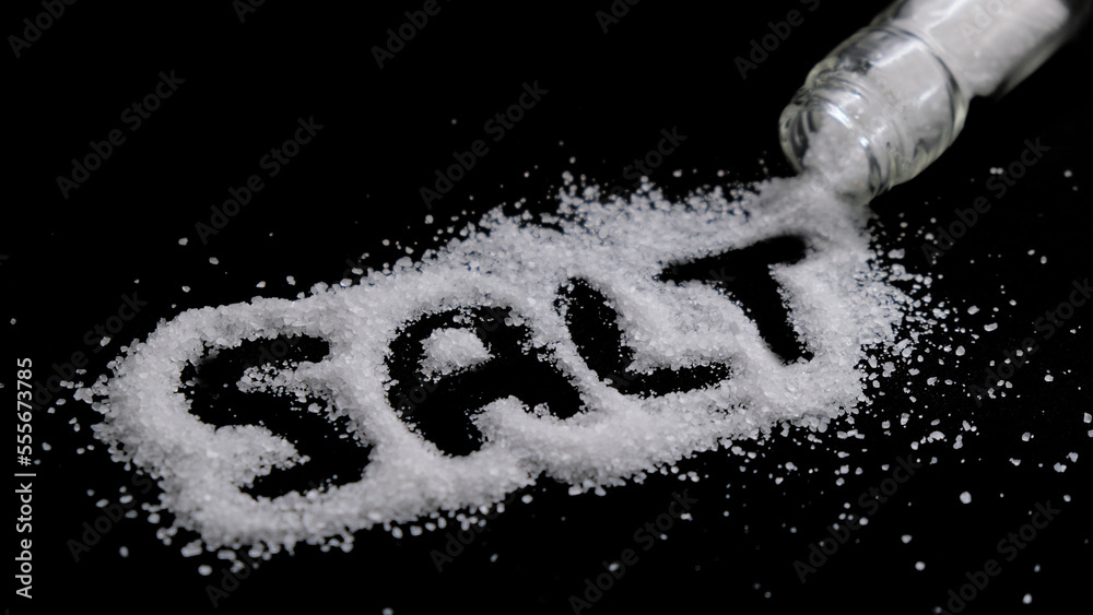 Salero abierto con sal cayendo en un fondo negro con la palabra sal ...