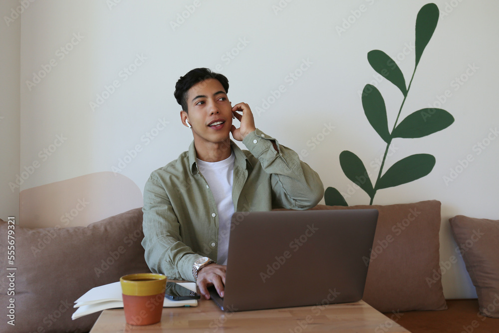 Hispanic young man sitting in coffee shop with his laptop and working ...