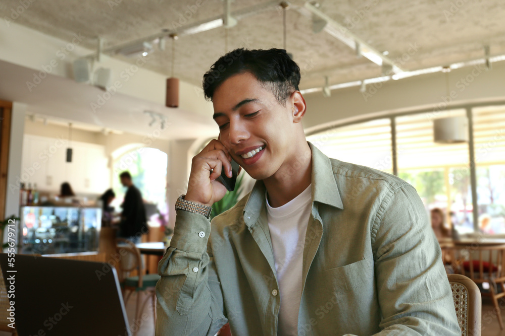 Hispanic young man sitting in coffee shop with his laptop and working ...