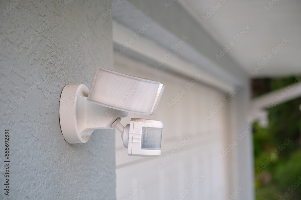 Motion sensor with light detector mounted on exterior wall of private ...