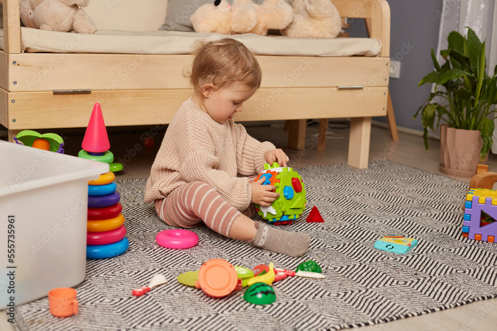 Cute little baby girl playing with colorful educational toys on carpet ...
