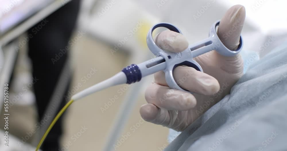 Close-up. The doctor holds an endoscopic biopsy clamp in his gloved ...