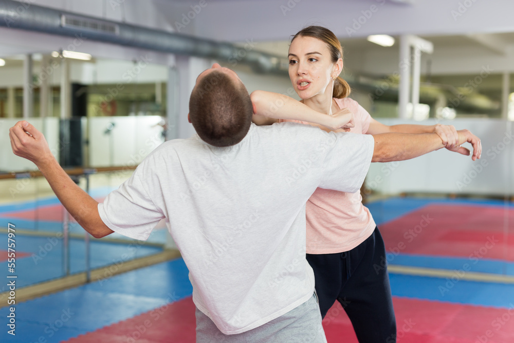 Caucasian woman performing elbow strike while sparring with man in gym ...