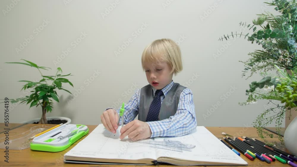 5 years old caucasian boy dressed very smart does homework in a big ...