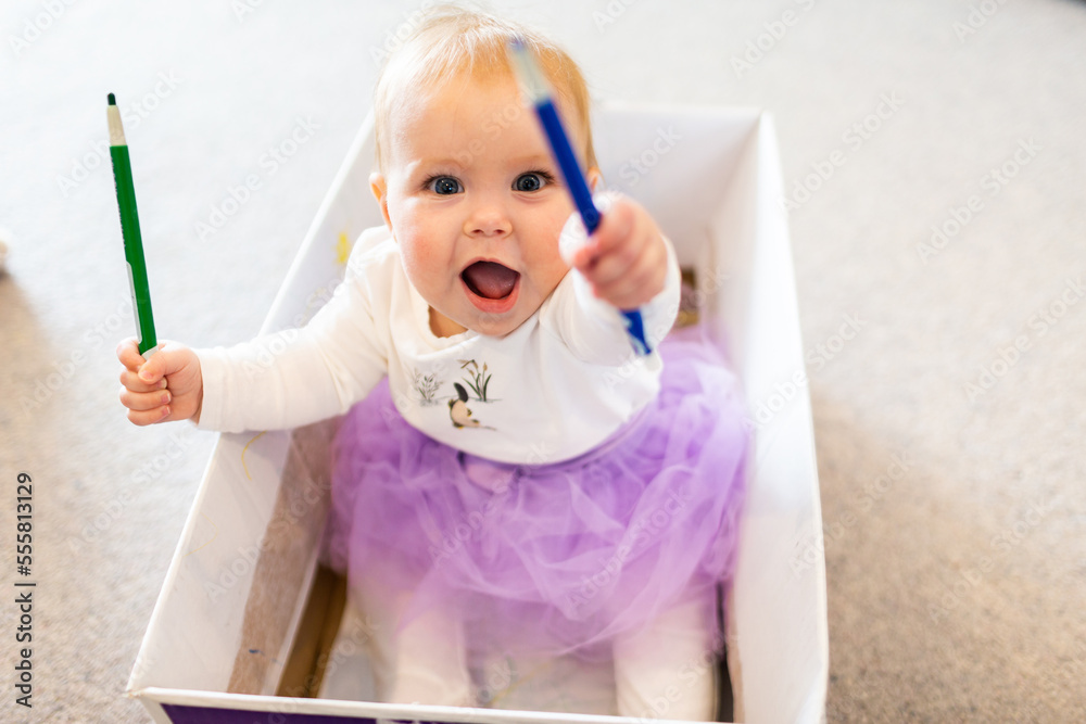 Baby girl sitting in box drawing with crayon textas at home Stock Photo ...